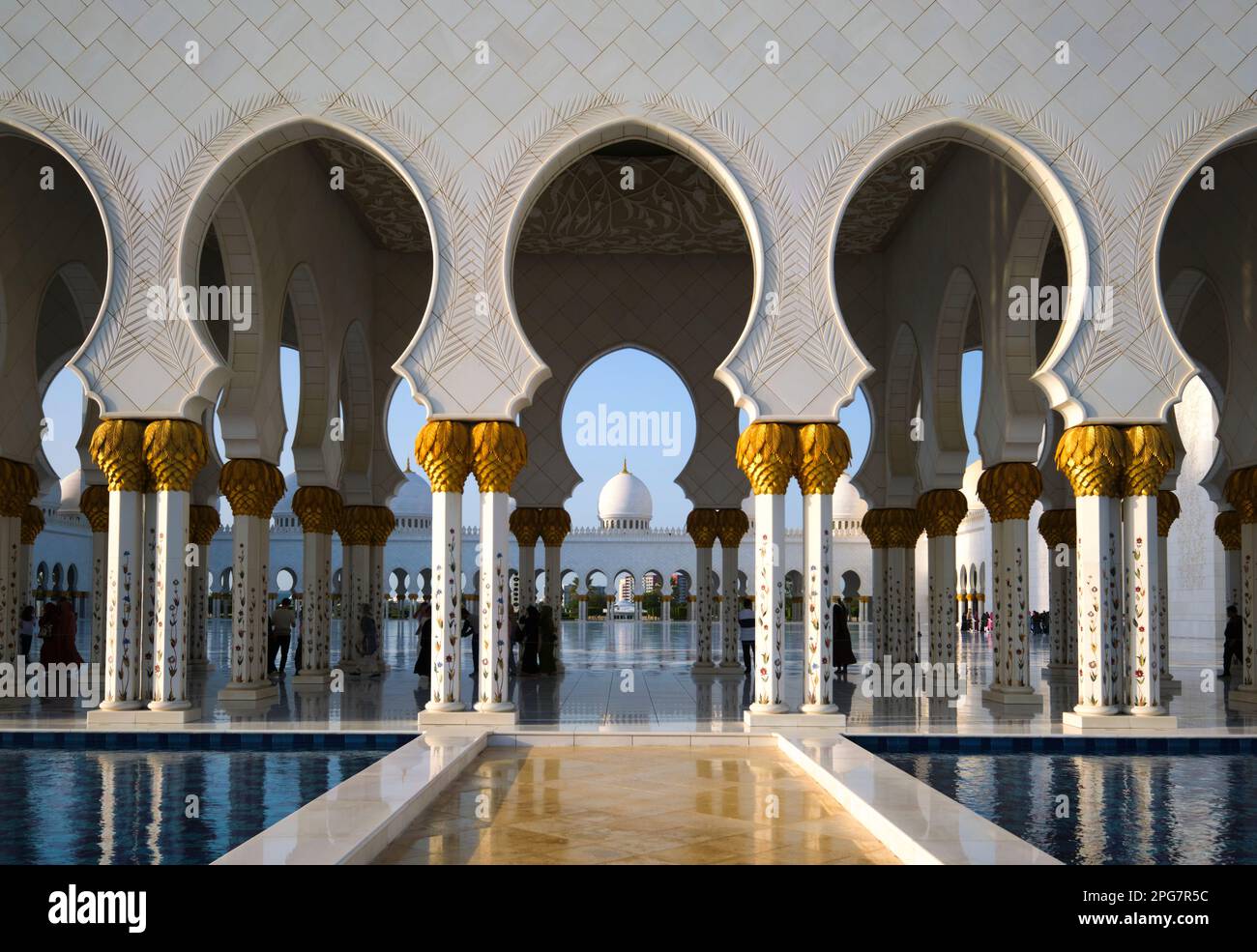 View of the walking, shaded portico with columns topped with painted ...