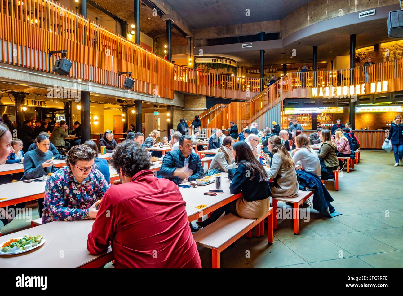 People sitting and eating at tables in a food court in the Seven Dials ...