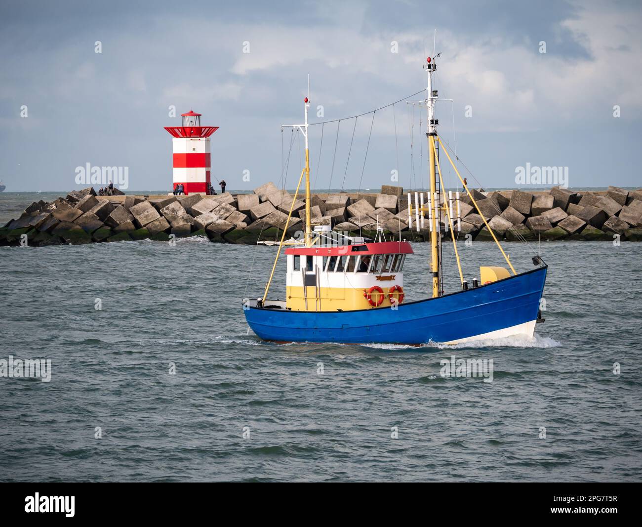 Small fishing boat and northern pier with red white beacon of ...