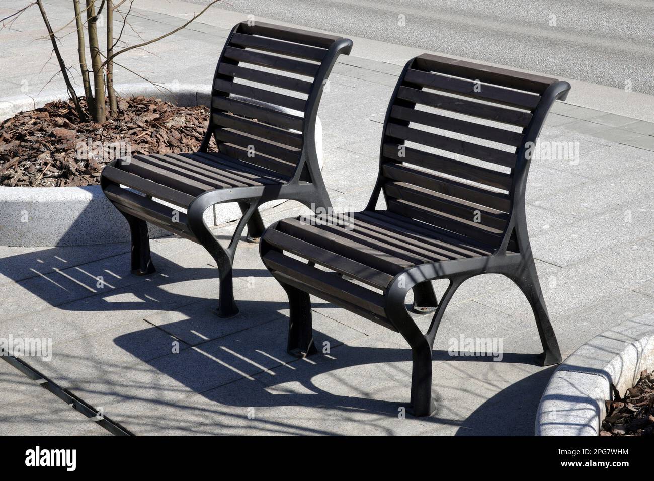 Two stylish street chairs as benches on the stone pavement in the city ...