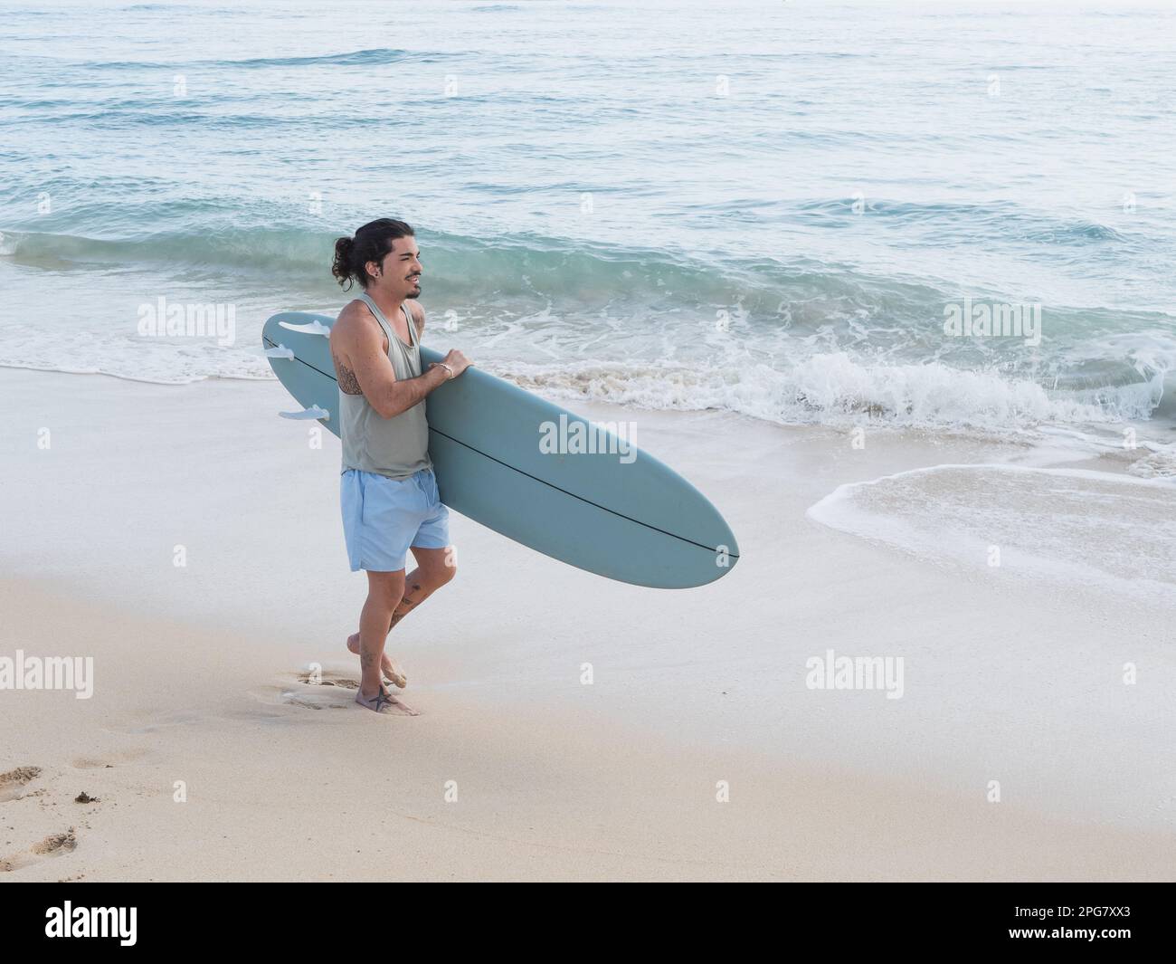 Hispanic surfer walking on the beach shore with his surfboard Stock ...