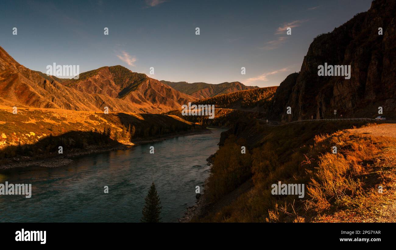 The mountain road Chuisky Trakt goes under a rock in the shade next to ...