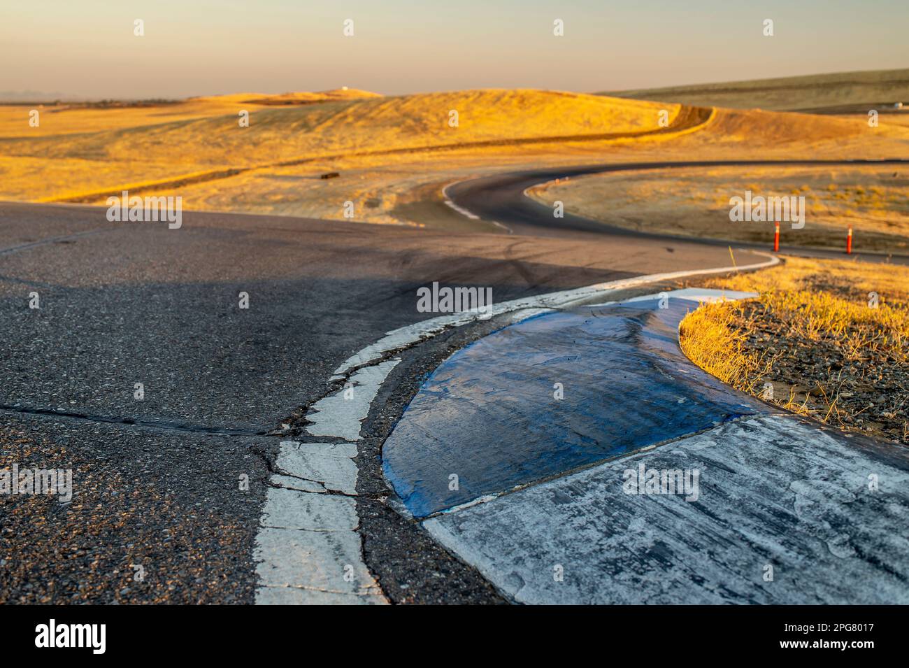 A view of a curved dirt road illuminated by the rising sun in ...