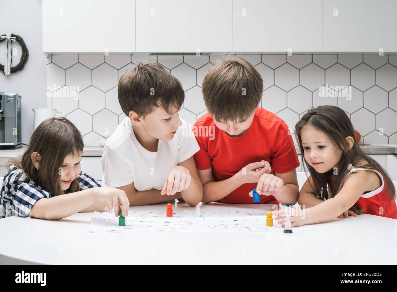 Four blissful, smiling kids playing board games and choosing colorful ...