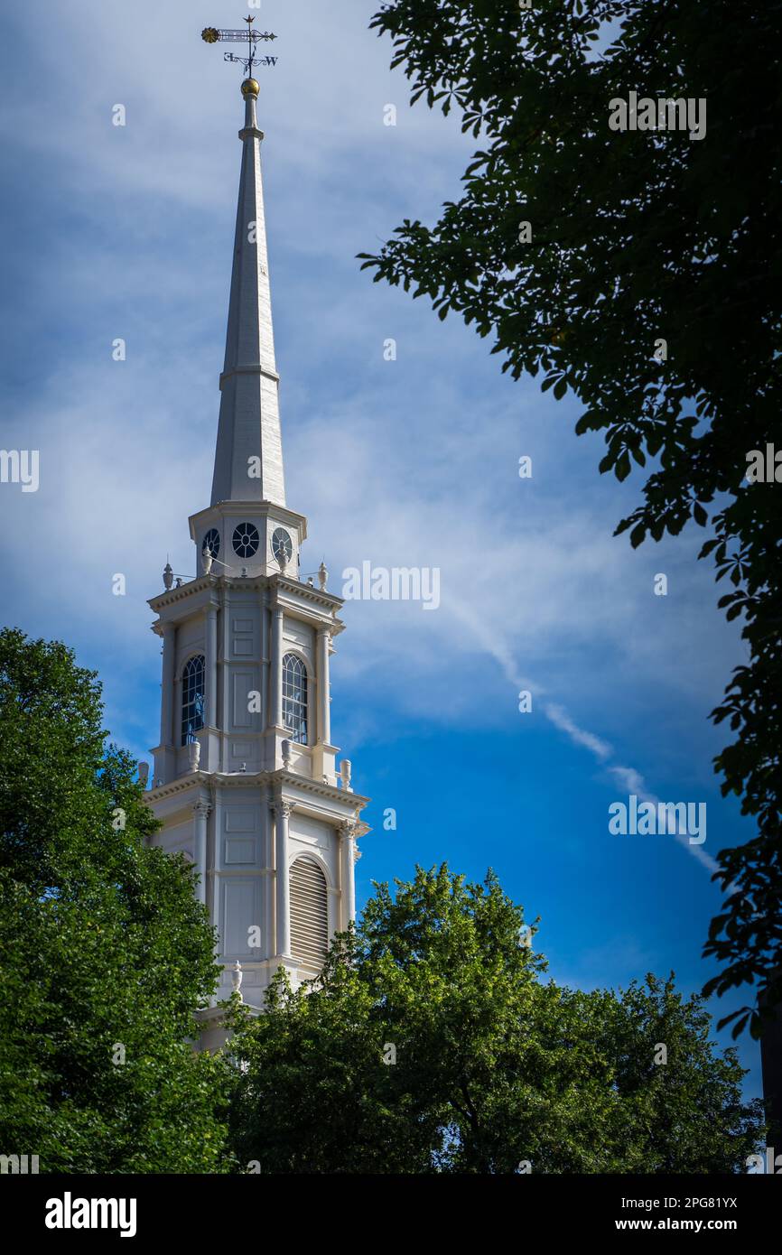An vertical shot of a park tree church tower rising high above a lush ...