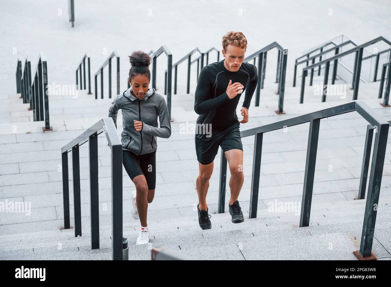 Running on bleachers. European man and african american woman in ...