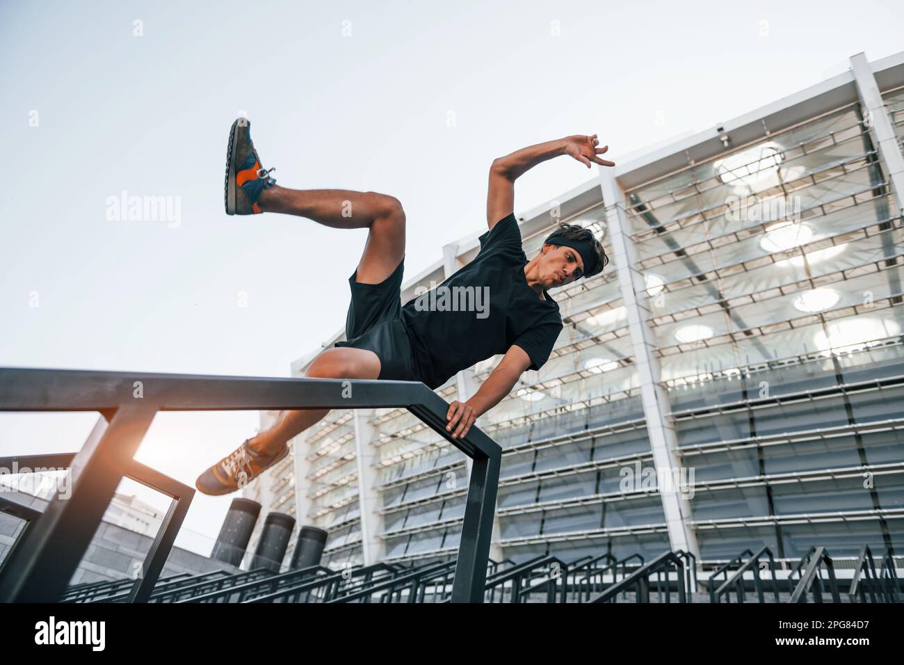 Does parkour. Young man in sportive clothes have workout outdoors at ...