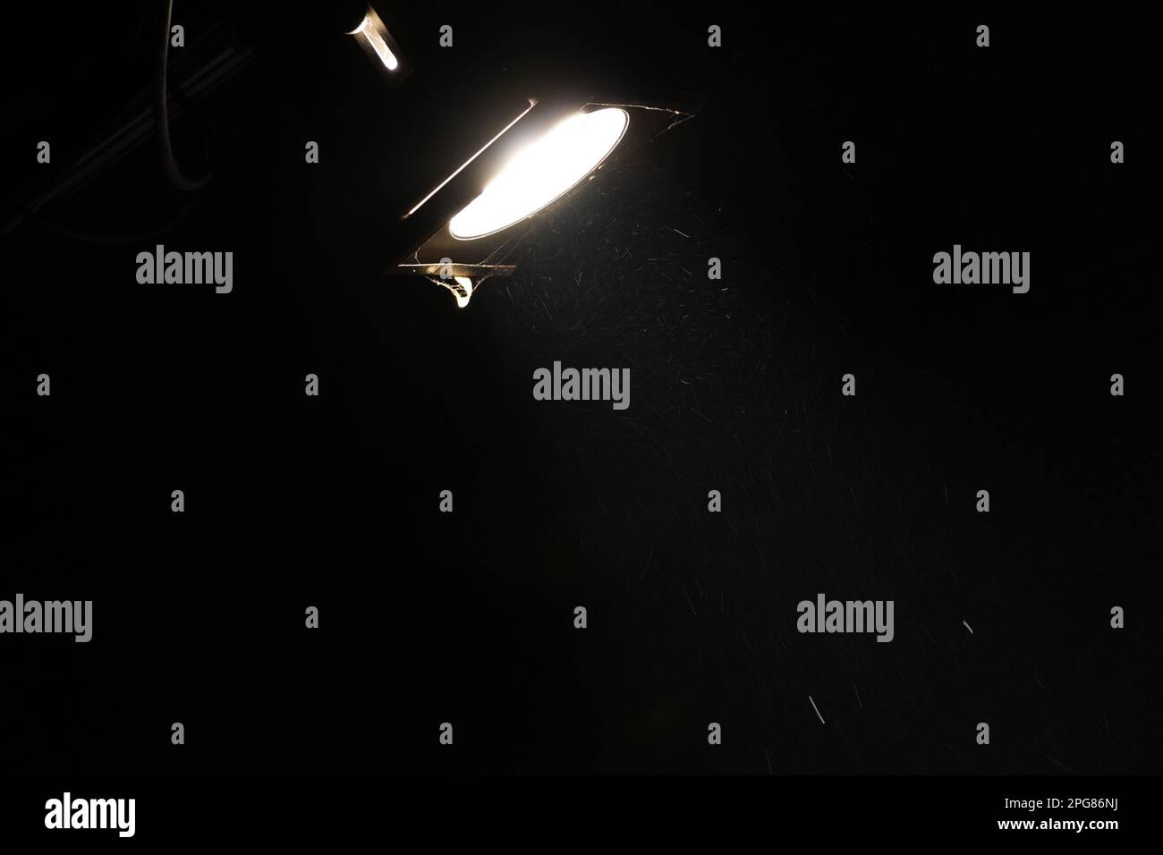 A bright lamp illuminating the dust particles in the air on the black ...