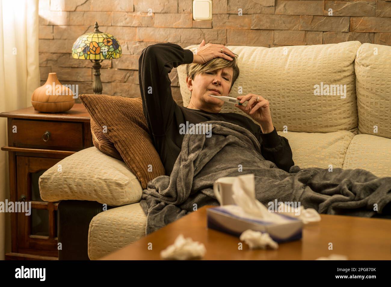 A woman looking at the thermometer with a concerned look on her face ...