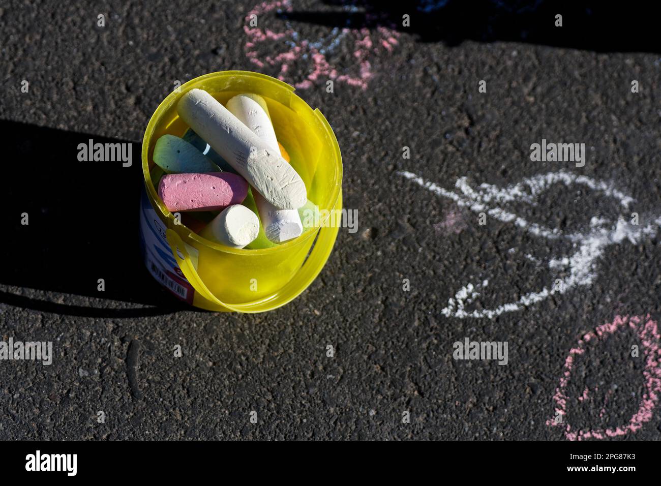 A small bright yellow bucket filled with colorful chalk pieces on a ...