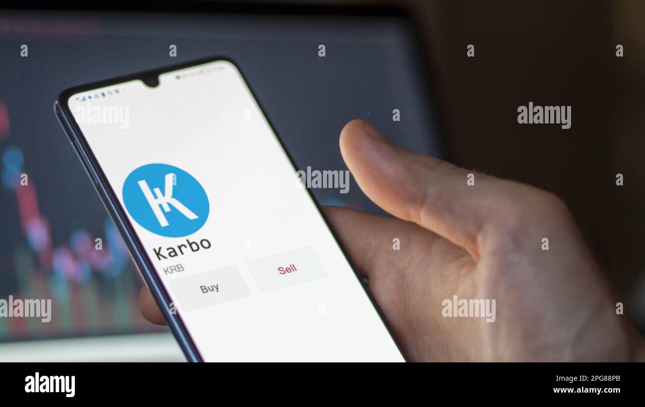 March 11 2023 London UK. An investor's analyzing the Karbo coin on screen. A phone shows the ETF ...