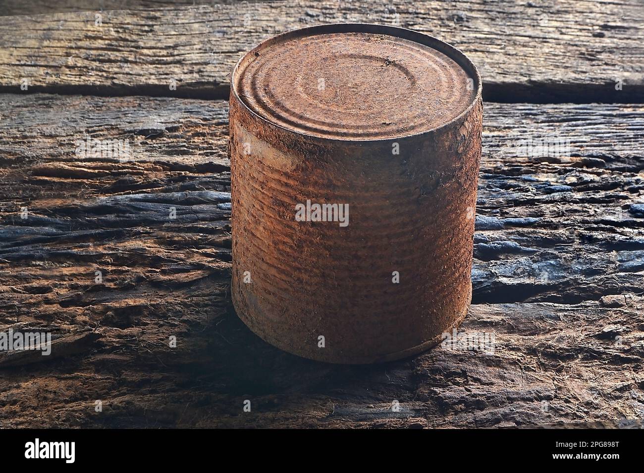 Rusty can, eight centimeters high, photographed on a rustic old wooden ...