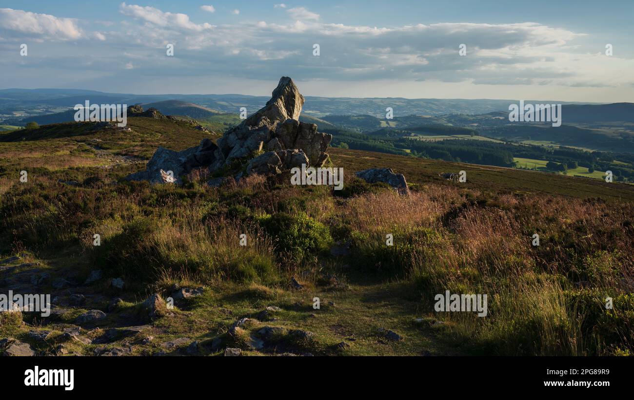 A scenic landscape featuring a hill covered in grass and rocky terrain ...