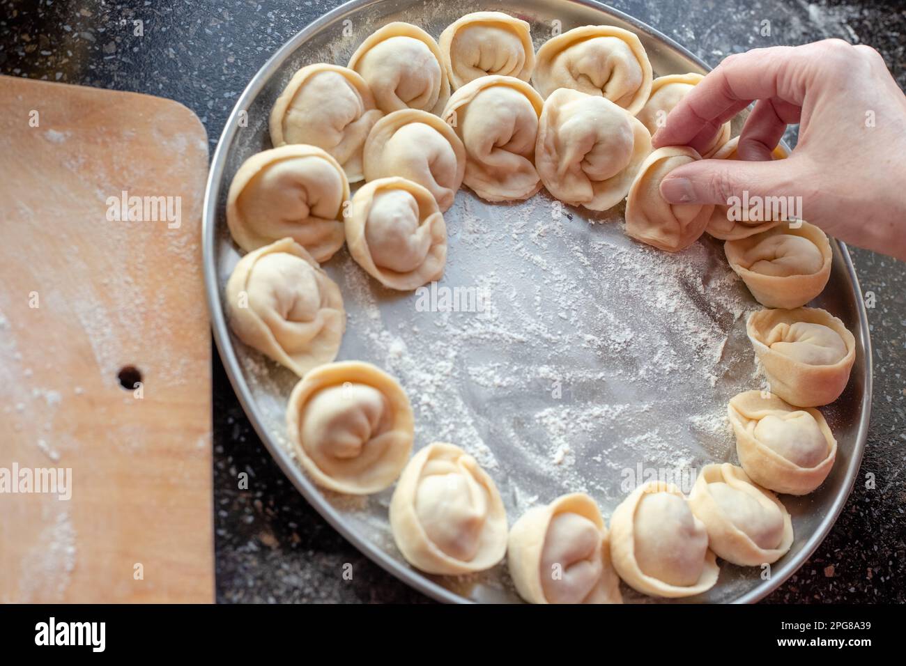 Cooking delicious national dish dumplings with meat. The woman puts the ...
