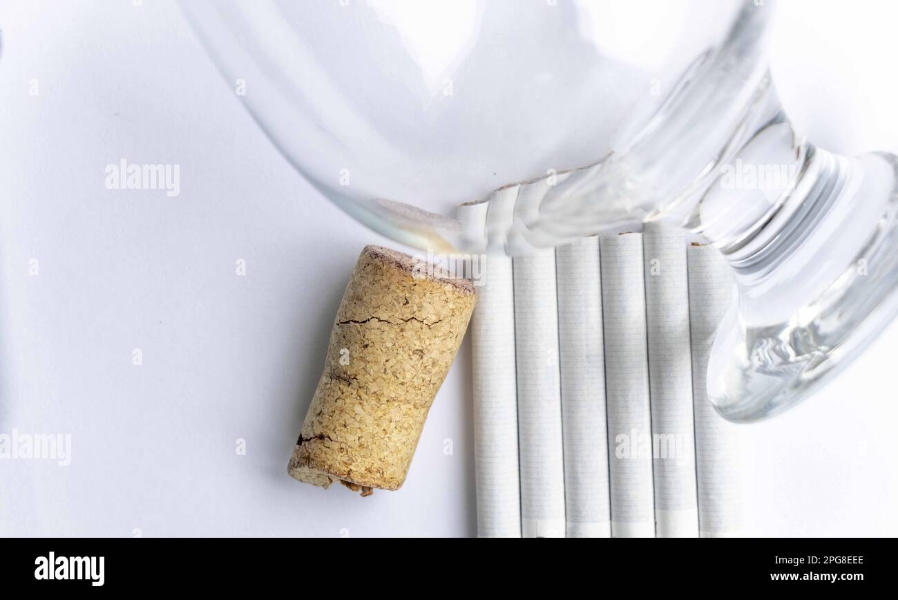 Empty wine glass and cork from wine and cigarettes on a white ...