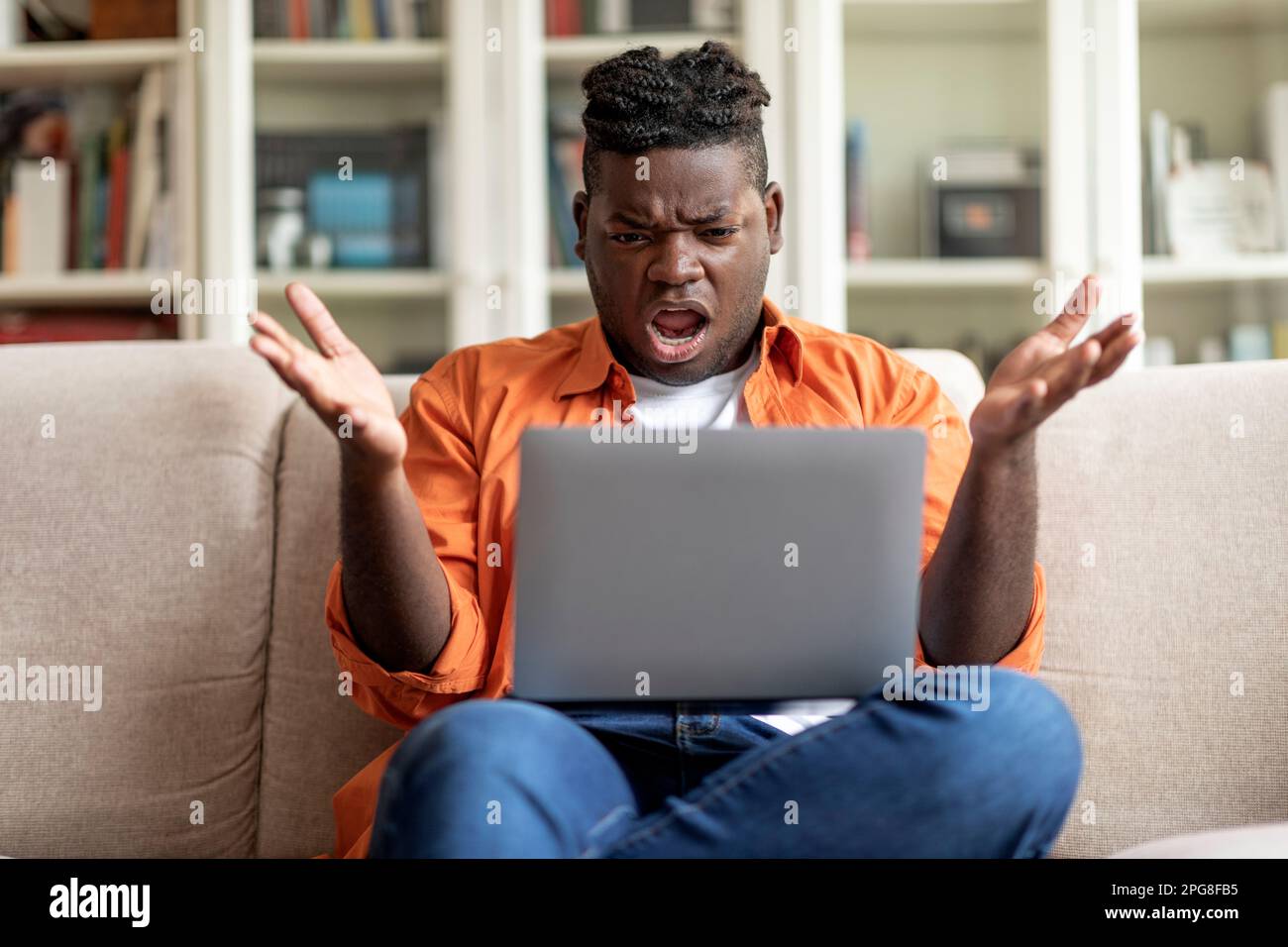 Angry african american man using laptop at home Stock Photo - Alamy