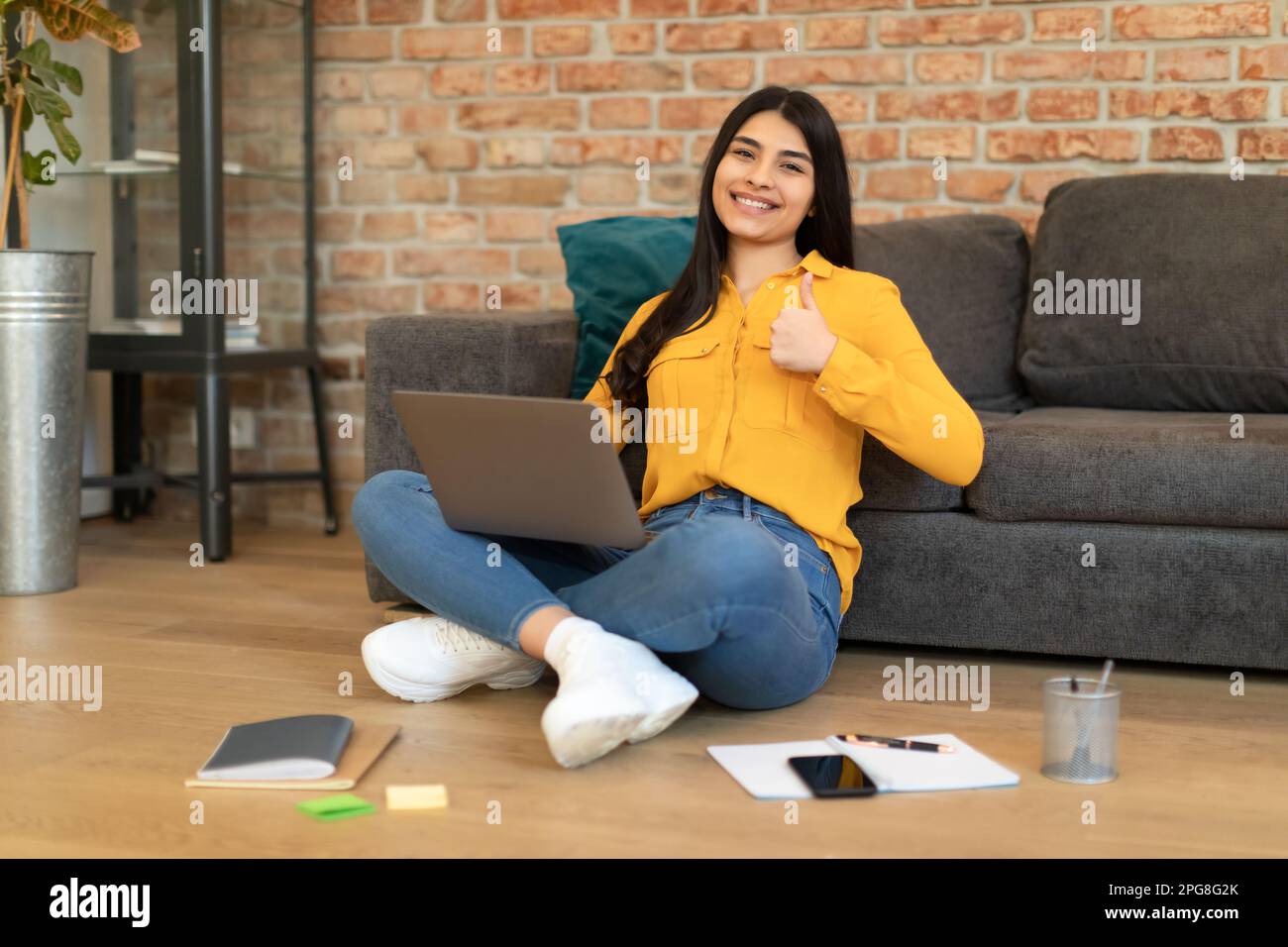 Happy spanish lady showing thumbs up gesture and using laptop, doing ...