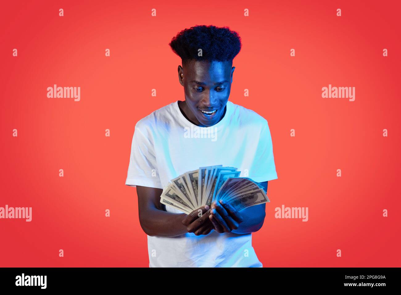 Emotional african american guy holding money cash Stock Photo - Alamy