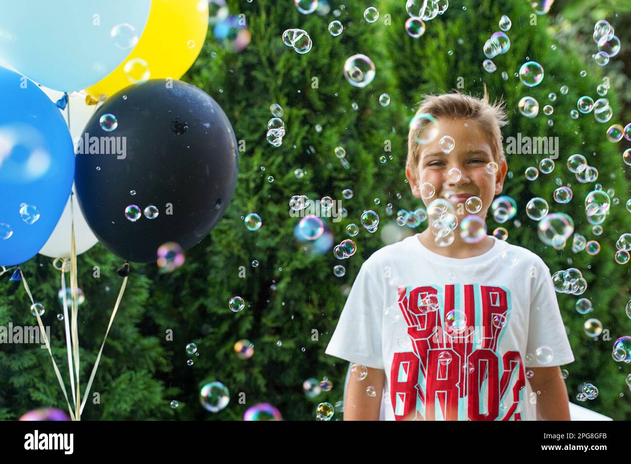 Portrait of a boy in flying soap bubbles. Soap party. Focus on flying ...