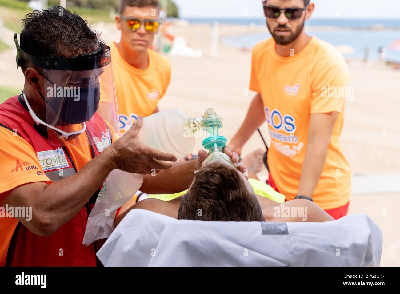 Close up photo of lifeguards giving oxygen to a man in a stretcher ...