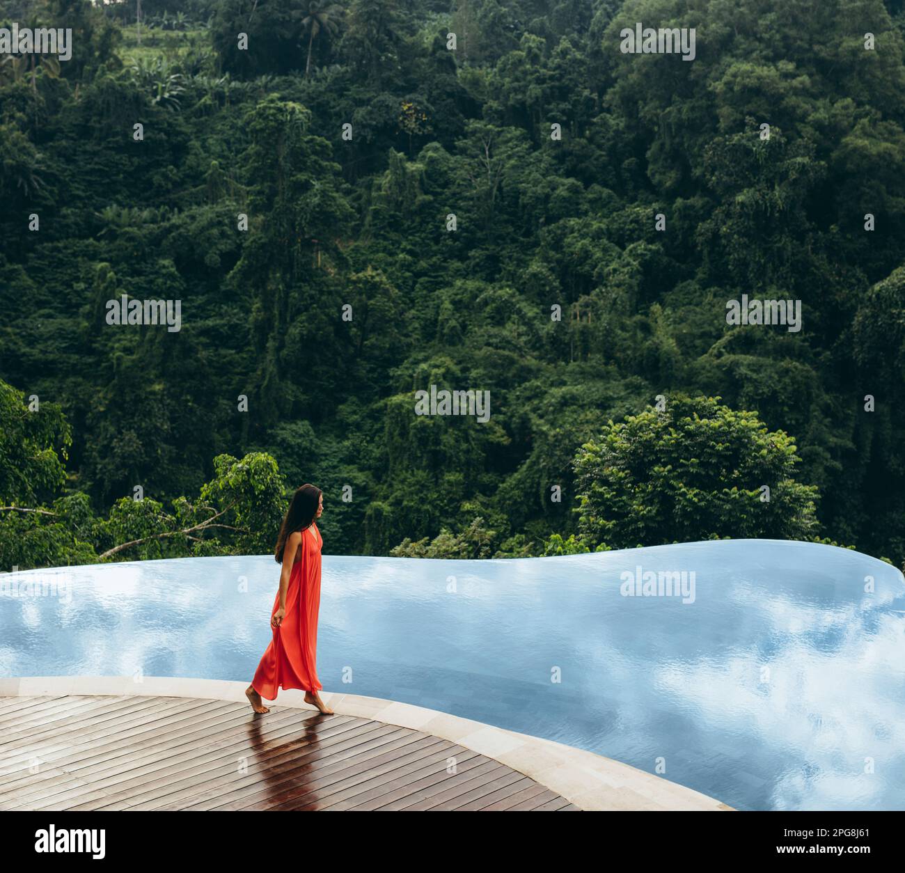 Shot of attractive young female walking on edge of infinity pool. Woman ...