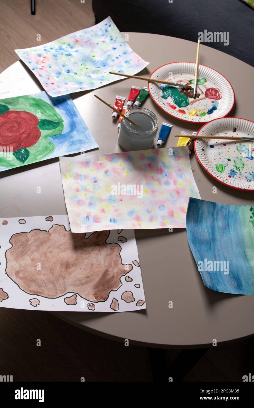 a photo of many sheets with drawings and colorful paints with brushes ...