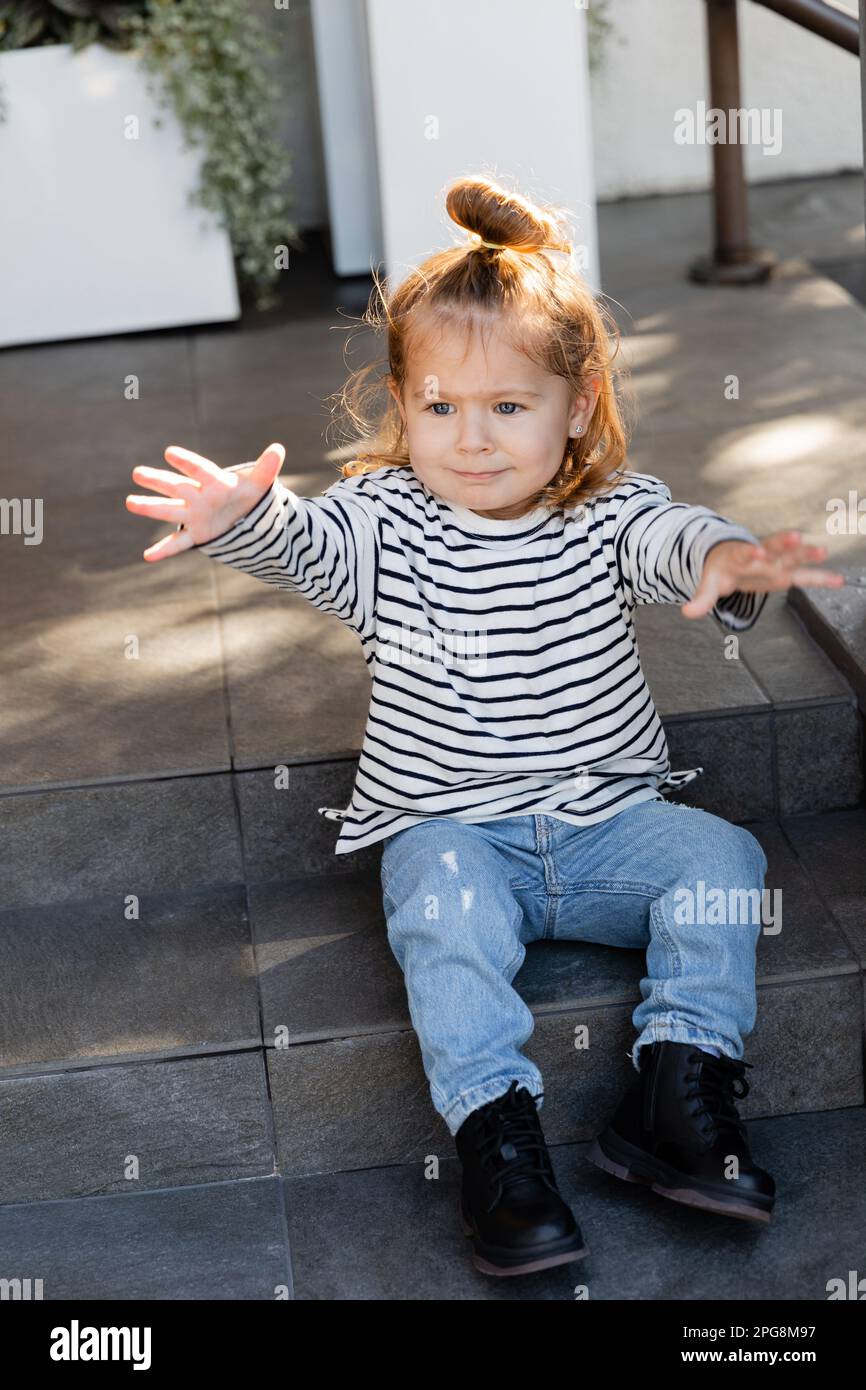toddler child in casual clothes demanding attention and gesturing while ...