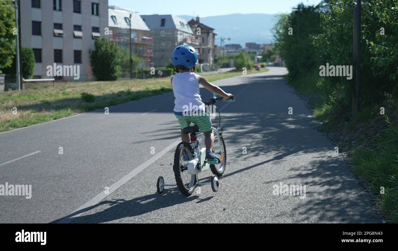 One sportive little boy riding bicycle in bike lane green city road ...