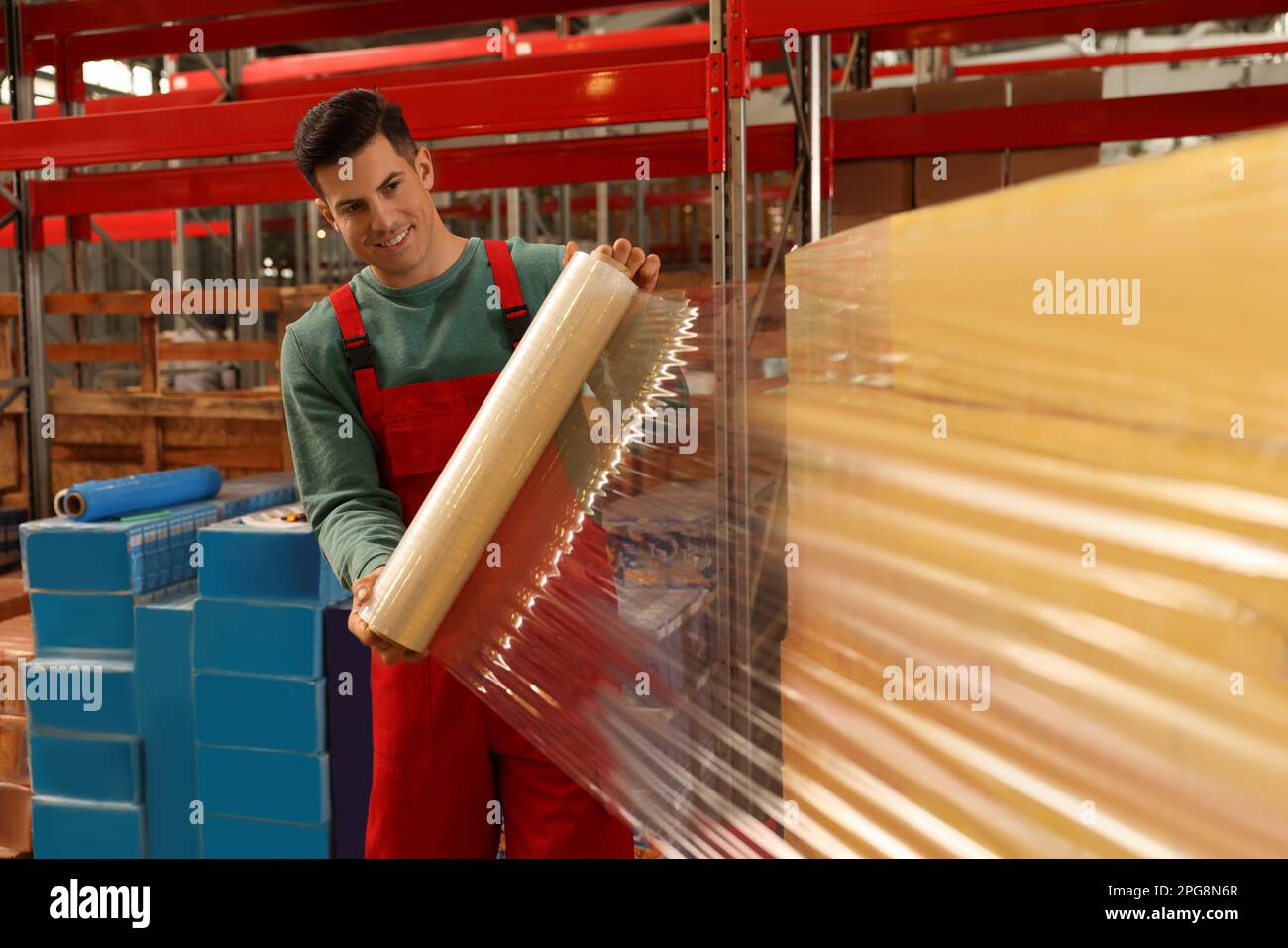 Worker wrapping boxes in stretch film at warehouse Stock Photo - Alamy
