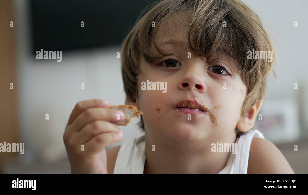 One small boy eating bread with peanut butter. Portrait of a child ...