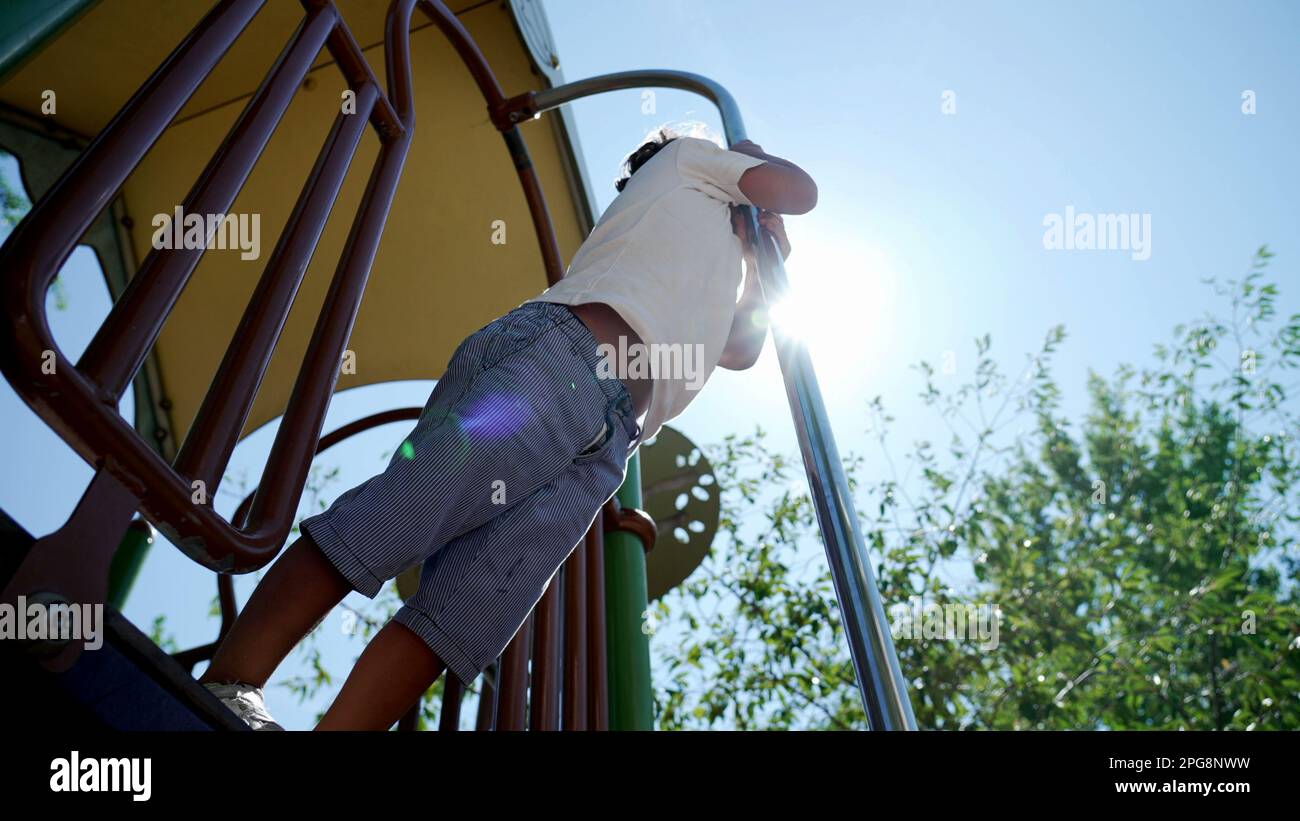 Kid slides down from playground metal pole during beautiful sunny day ...