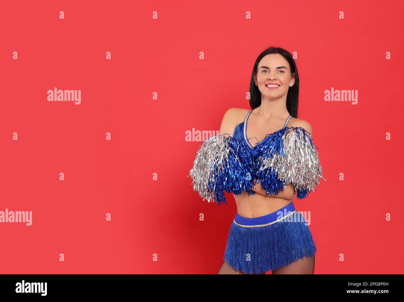 Beautiful cheerleader in costume holding pom poms on red background ...