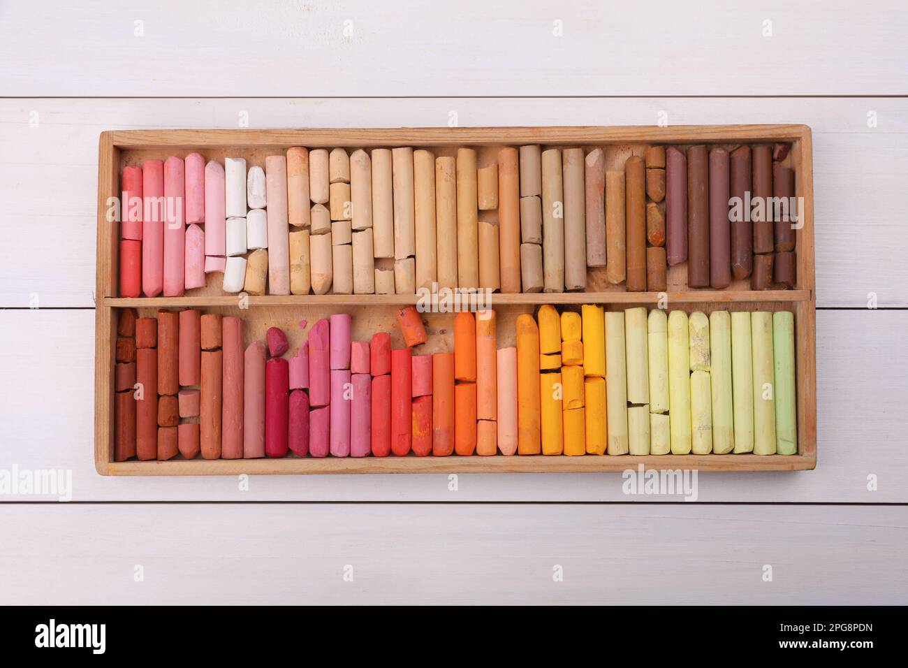 Set of soft pastels in box on white wooden table, top view. Drawing ...