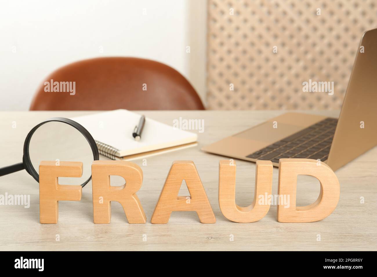 Word Fraud made of wooden letters near laptop and magnifying glass on ...