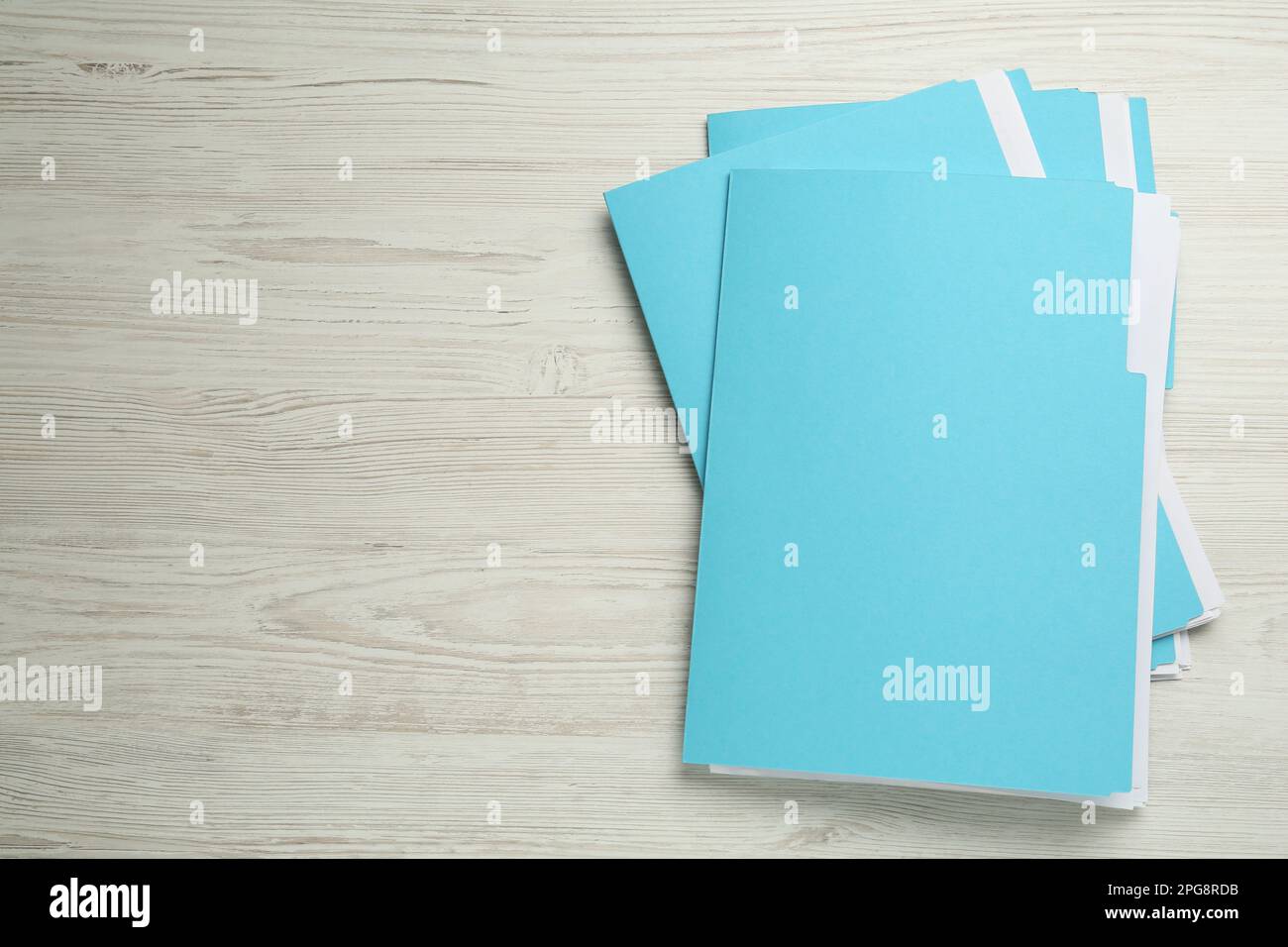 Turquoise files with documents on white wooden table, top view. Space ...