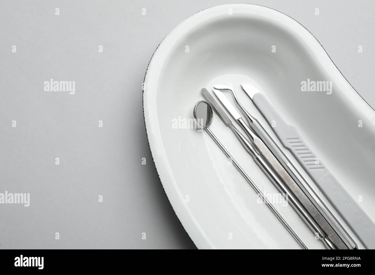 Kidney shaped tray with set of dentist's tools on light grey background ...