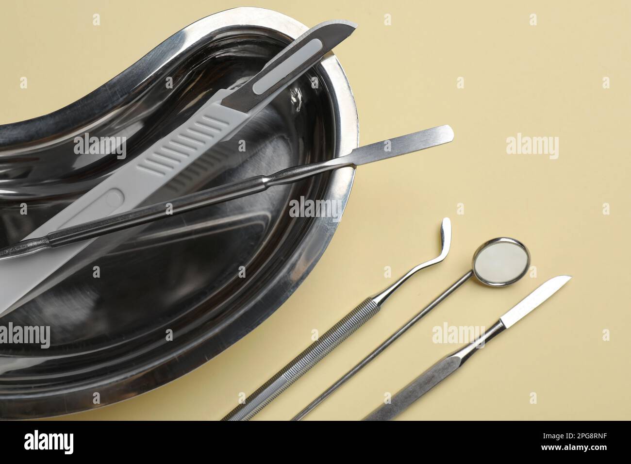 Kidney shaped tray with set of dentist's tools on pale yellow ...