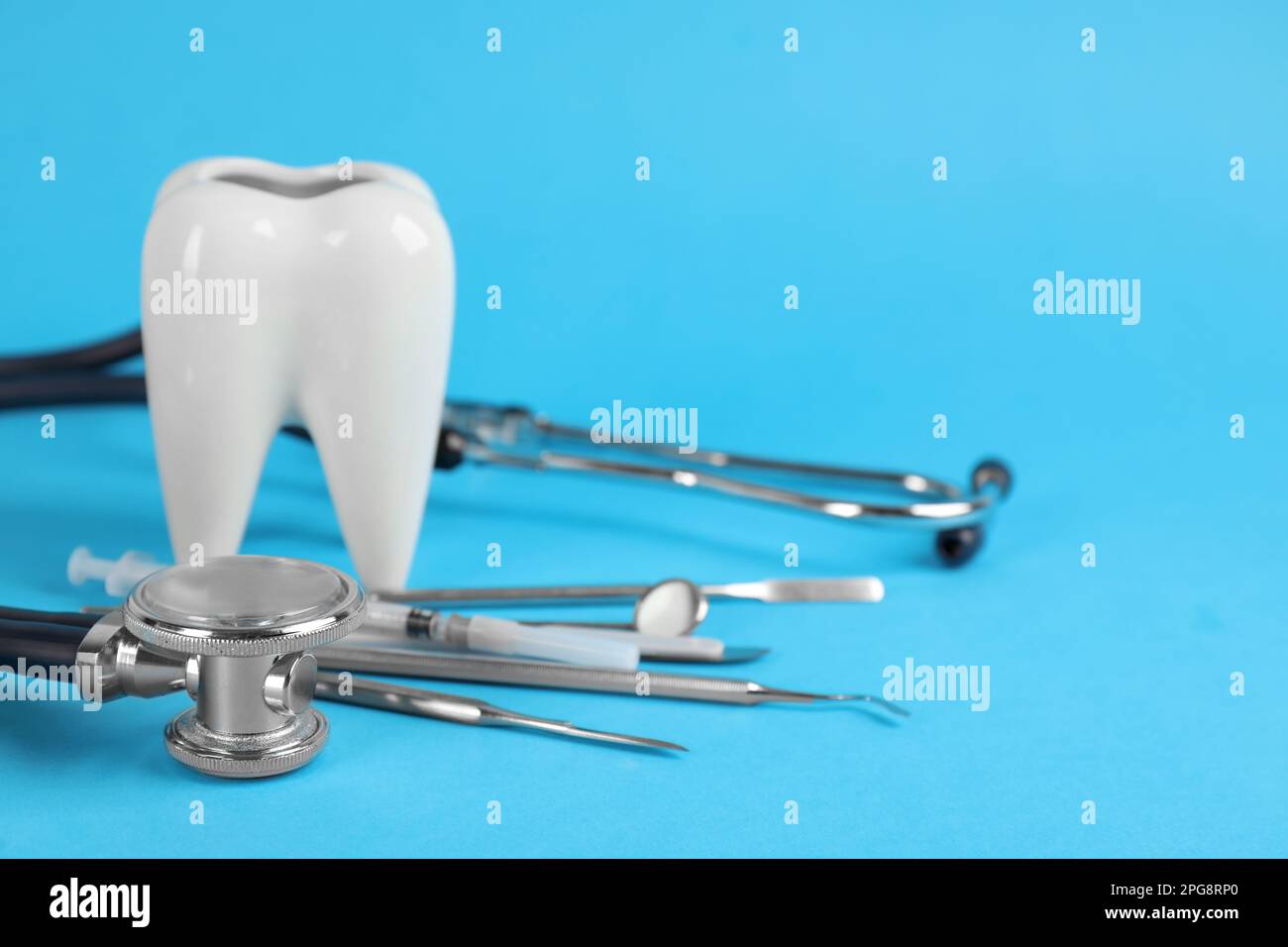 Tooth shaped holder, different dentist's tools and stethoscope on light ...