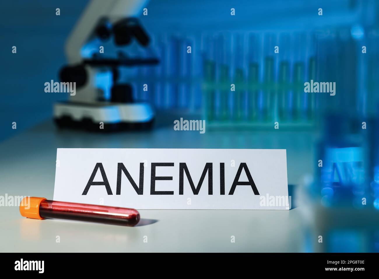 Test tube with blood sample and inscription Anemia on white table in ...