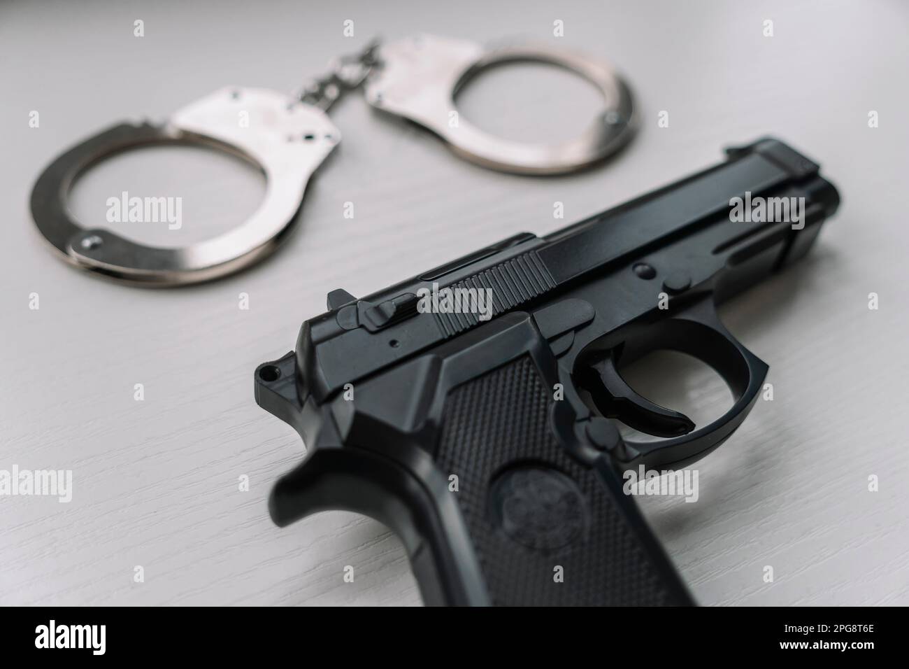 Black handgun gun with handcuffs on wooden surface. Arrest concept ...