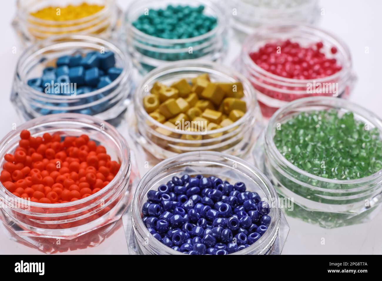 Plastic containers with different beads on white background, closeup ...