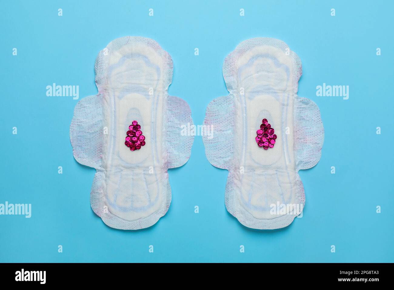 Menstrual pads with drops made of pink sequins on light blue background ...