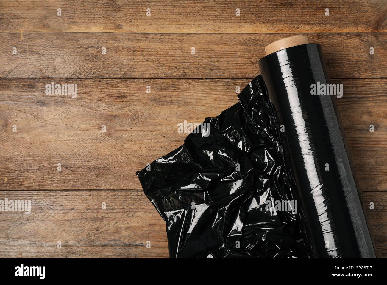 Roll of plastic stretch wrap film on wooden table, top view. Space for ...