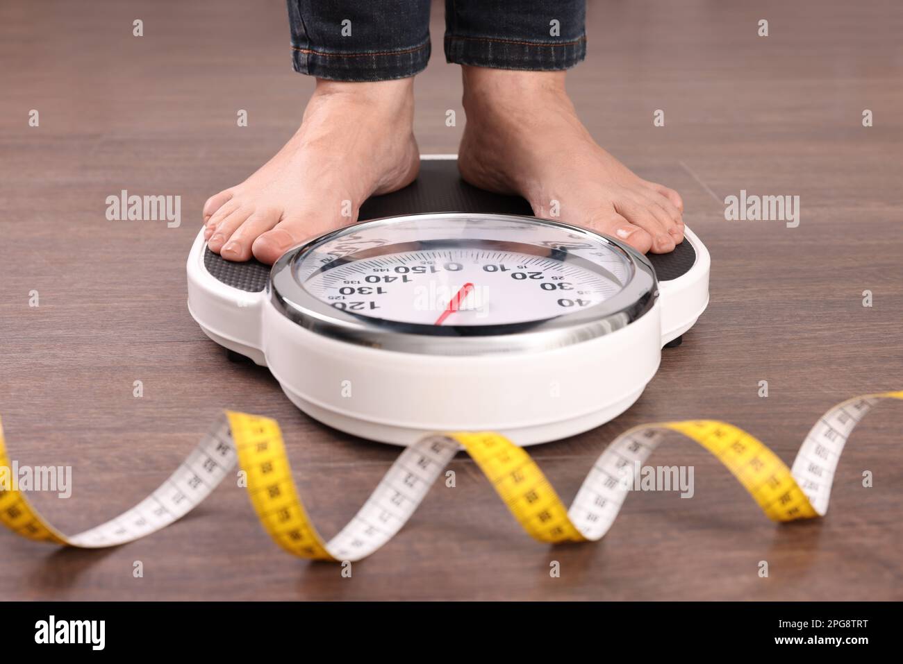Woman using scales on floor near measuring tape, closeup. Overweight ...