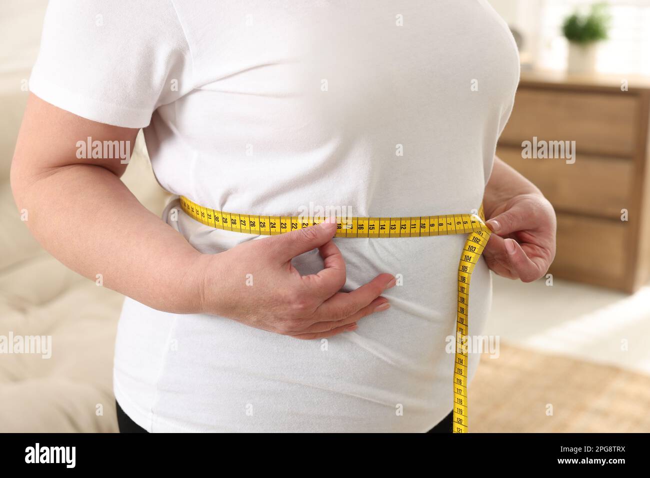 Overweight woman measuring waist with tape at home, closeup Stock Photo ...