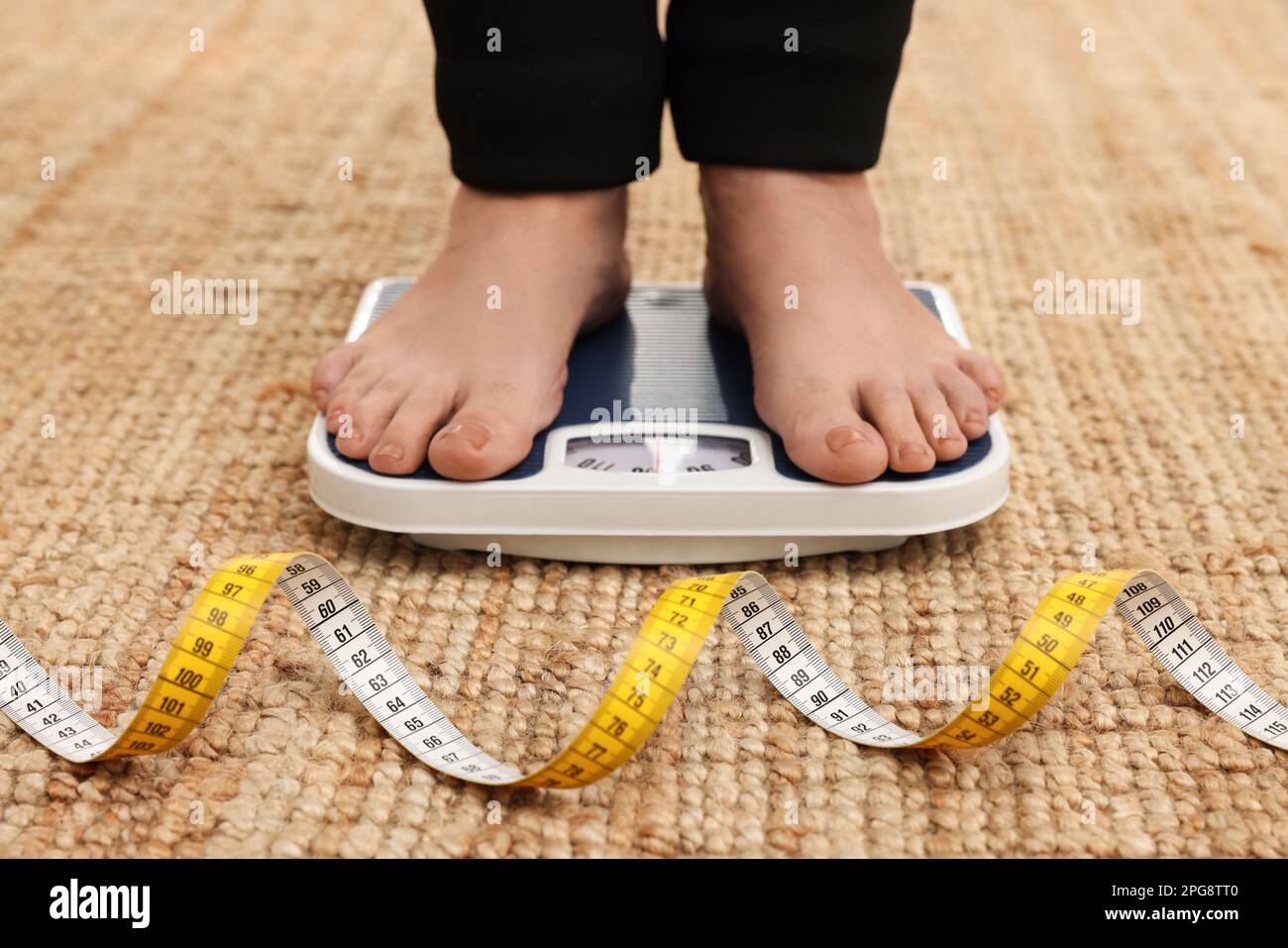 Woman using scales on carpet near measuring tape, closeup. Overweight ...