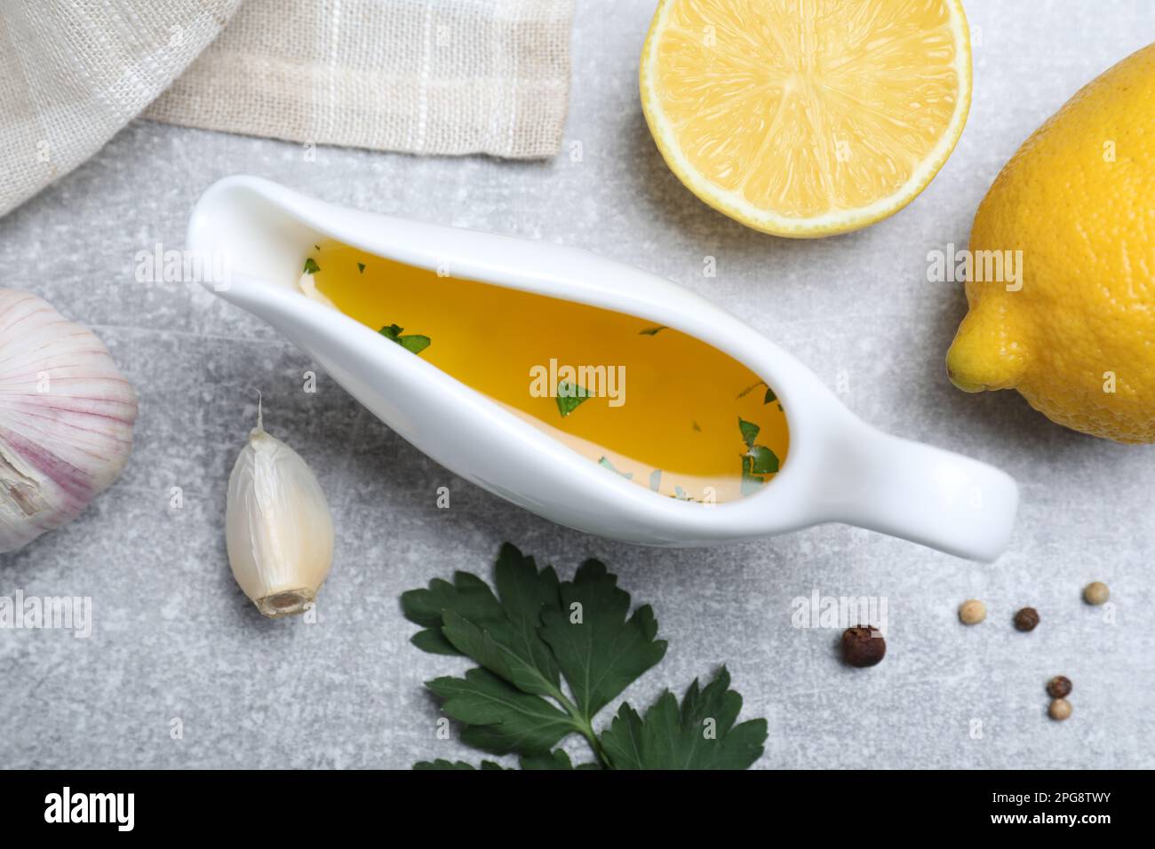 Ceramic boat with lemon sauce and ingredients on light grey table, flat ...