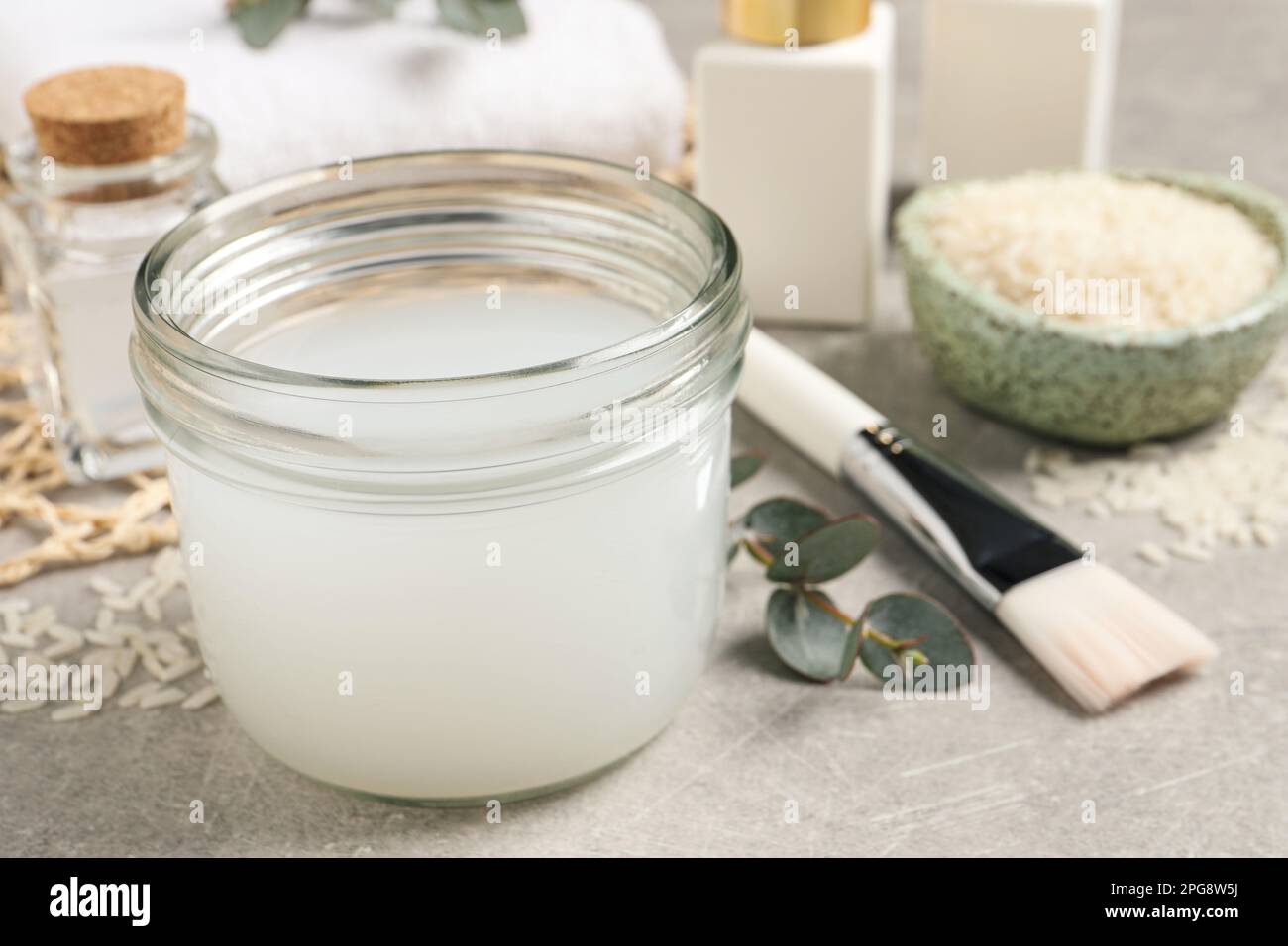 Homemade natural rice water and cosmetic products on light grey table ...