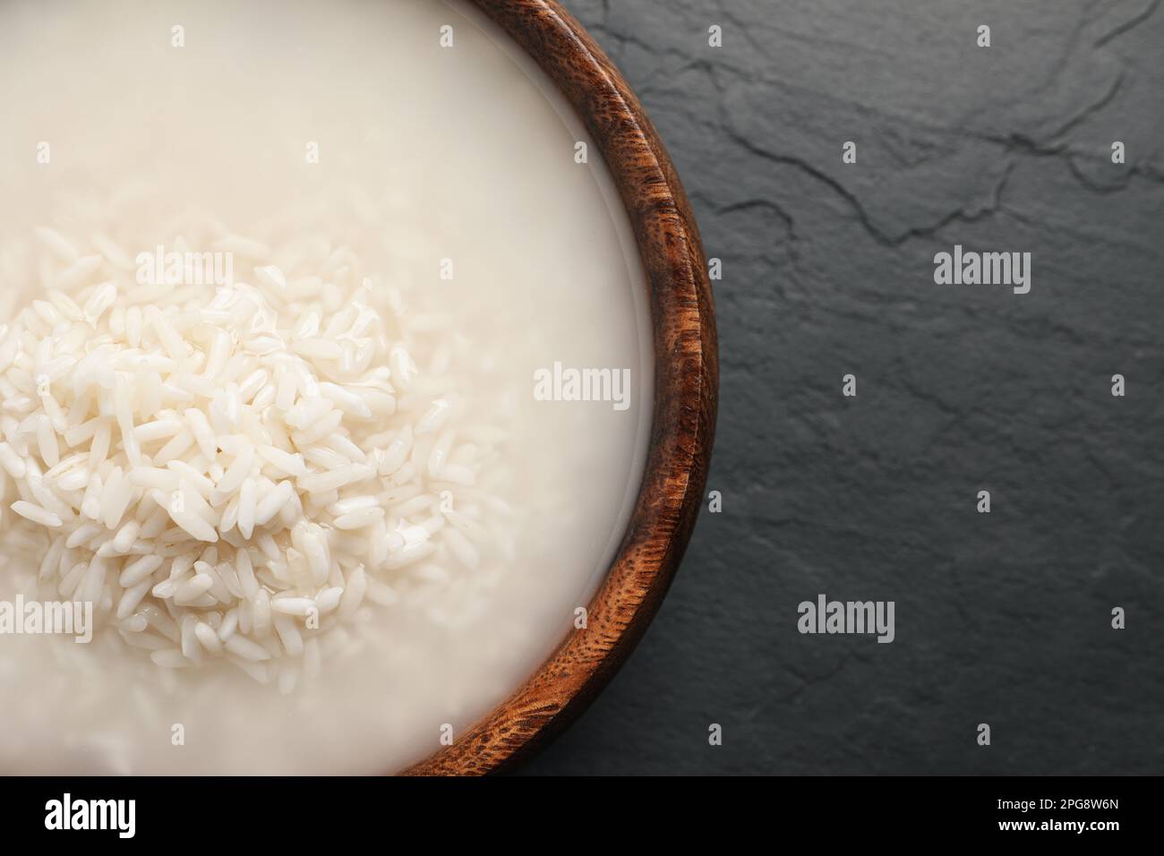 Rice soaked in water on black table, top view. Space for text Stock ...