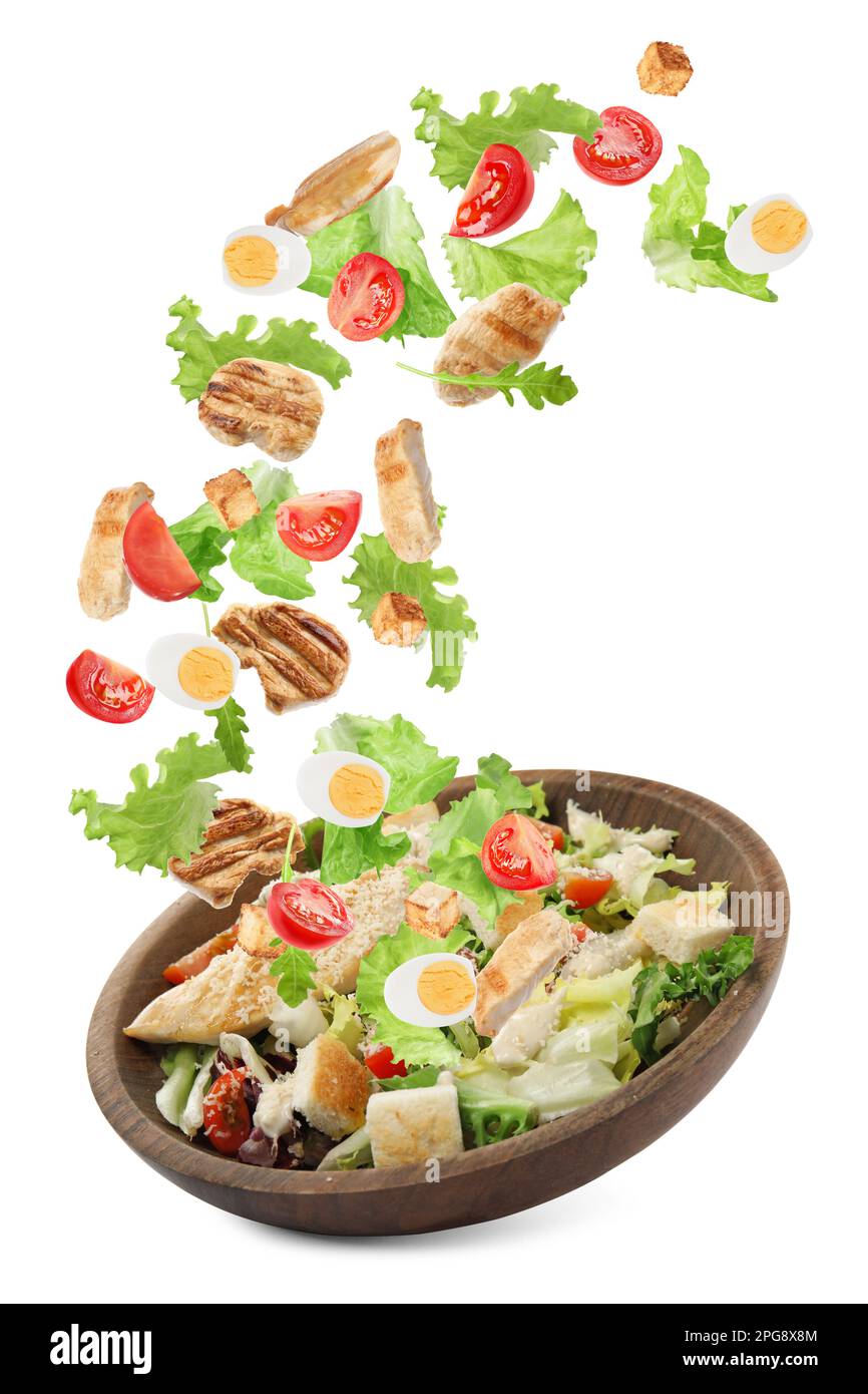 Tasty ingredients for Caesar salad falling into plate on white ...